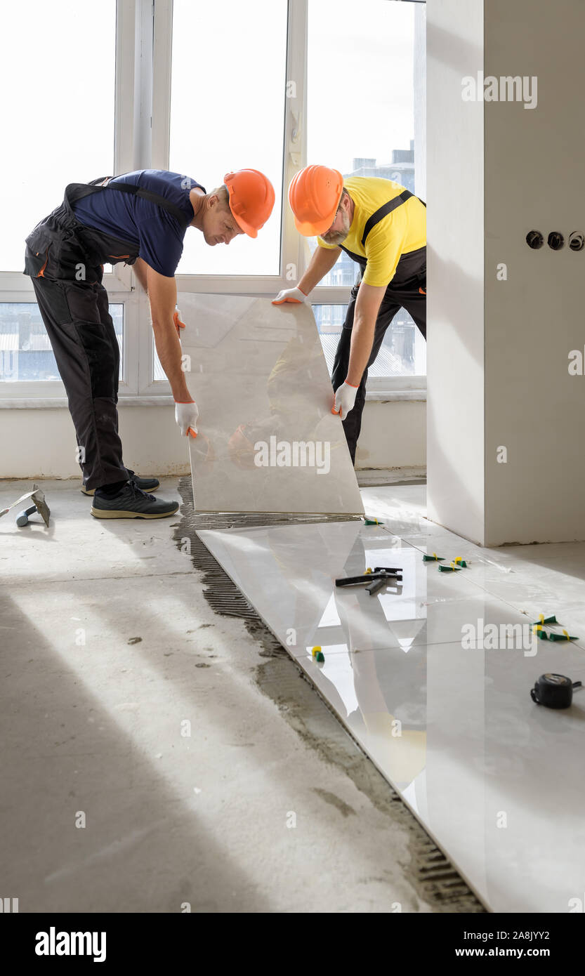 Workers are installing a large ceramic tile on the floor Stock Photo ...