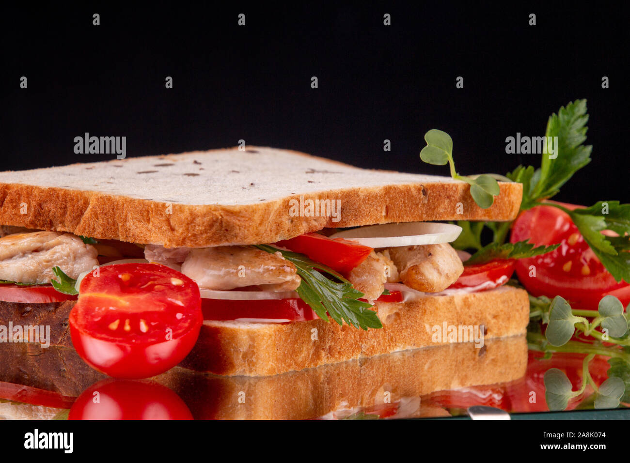 Sandwich with chicken meat, cherry tomato and onion on a mirror surface ...
