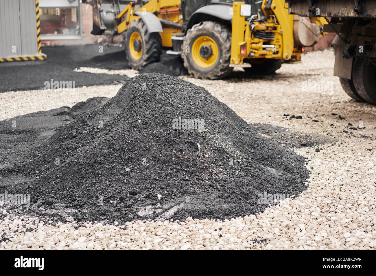Heap new hot asphalt. Laying asphalt, covering the pit, on the rubble ...