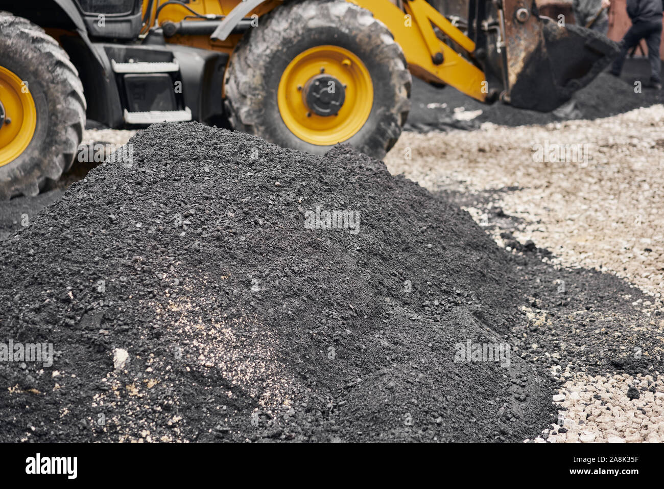 Heap new hot asphalt. Laying asphalt, covering the pit, on the rubble ...
