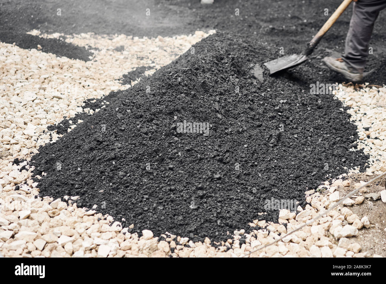 Laying new asphalt, covering the pit, on the rubble. Workers carry in ...