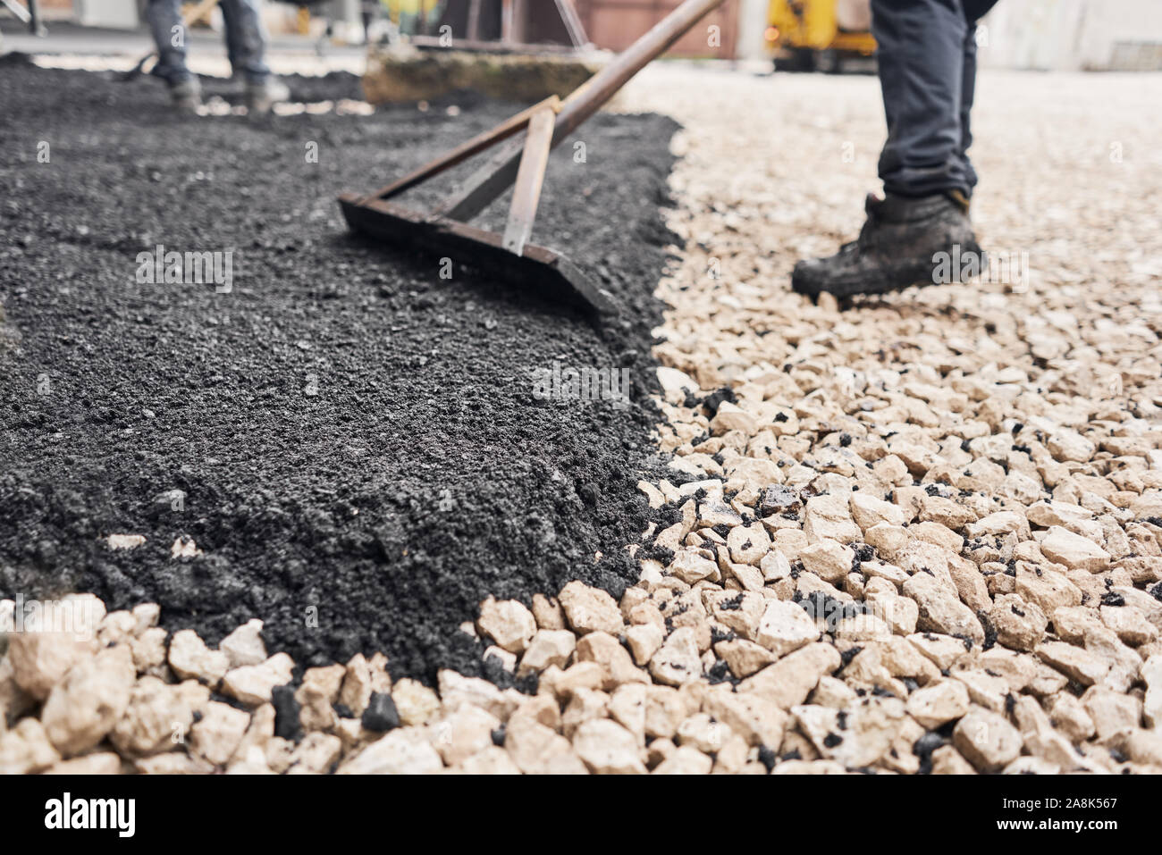 Laying new asphalt, covering the pit, on the rubble. Workers carry in ...