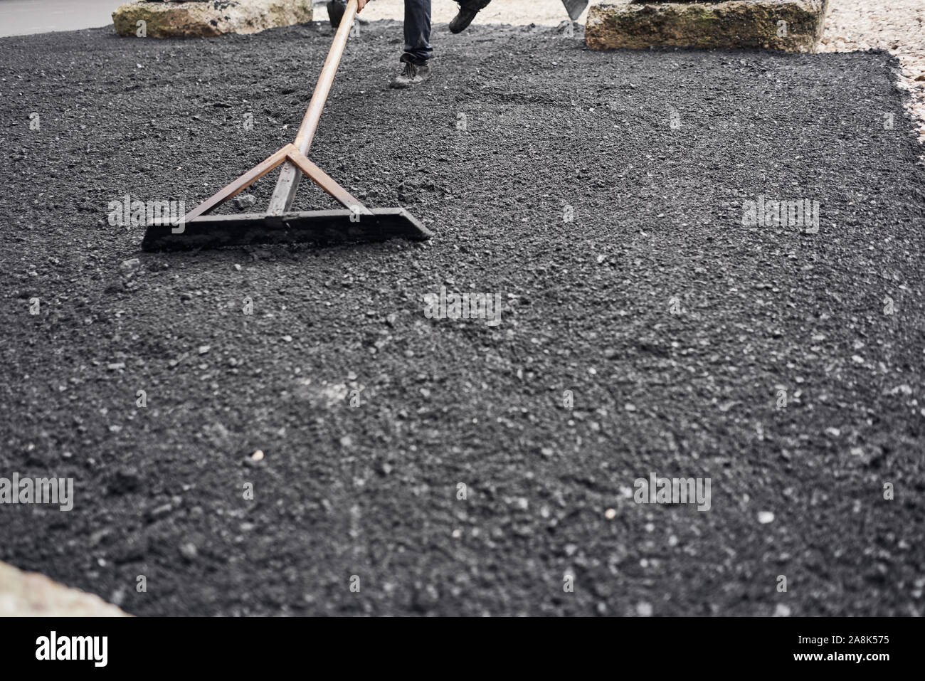 Laying new asphalt, covering the pit, on the rubble. Workers carry in ...