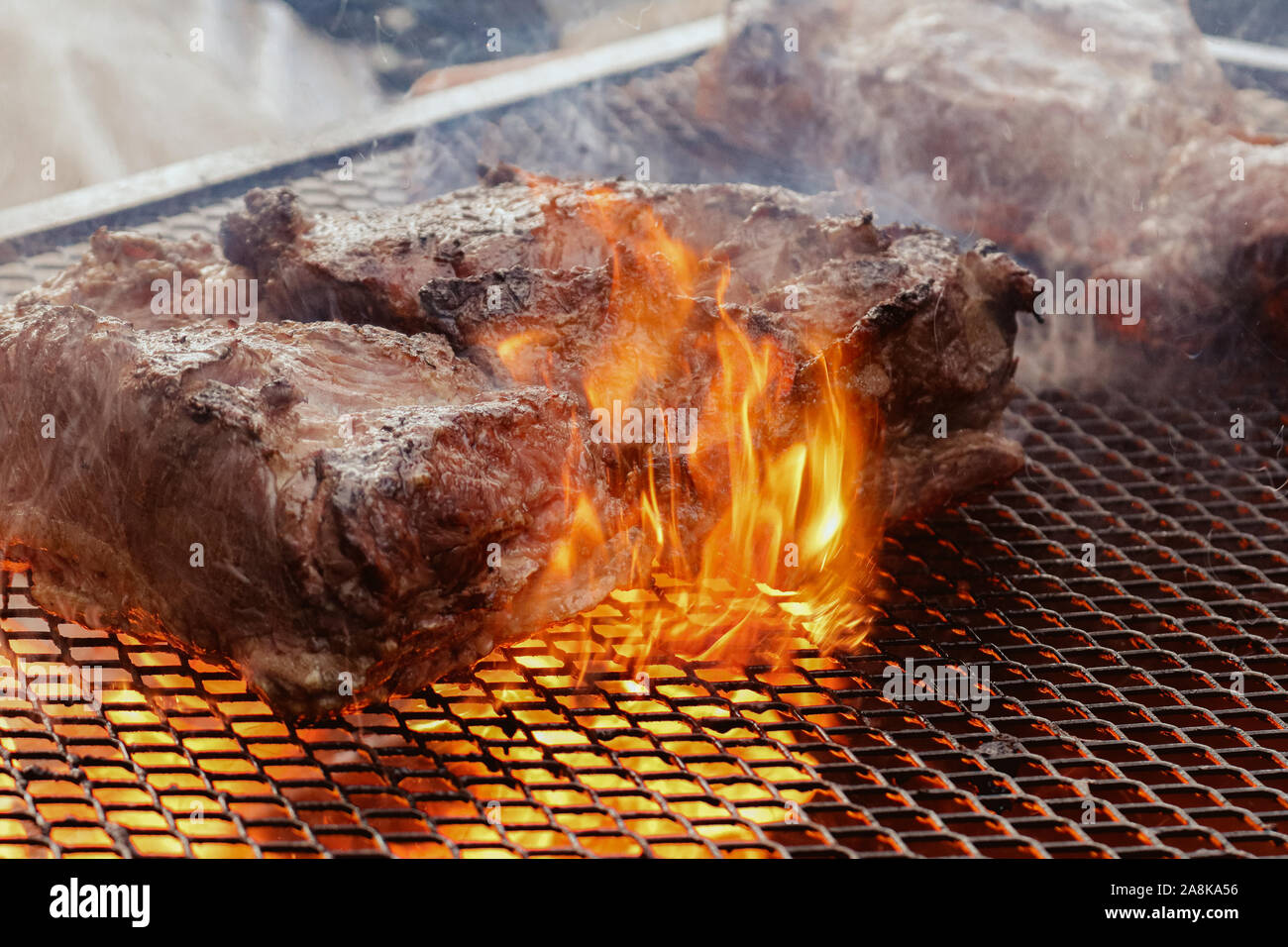a barbecue grill of bricks on fire with some pieces of meat on top of ...