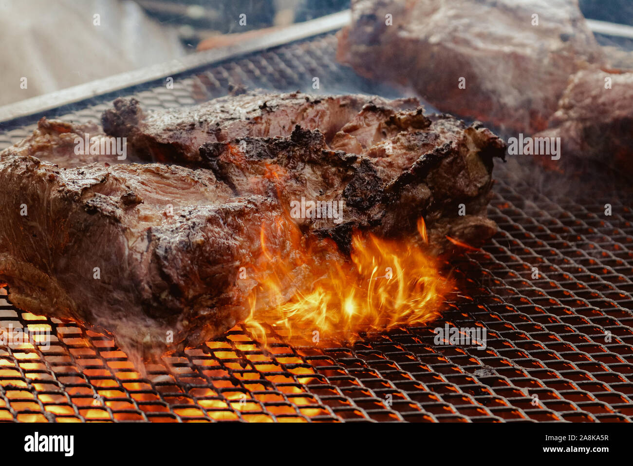 a barbecue grill of bricks on fire with some pieces of meat on top of ...