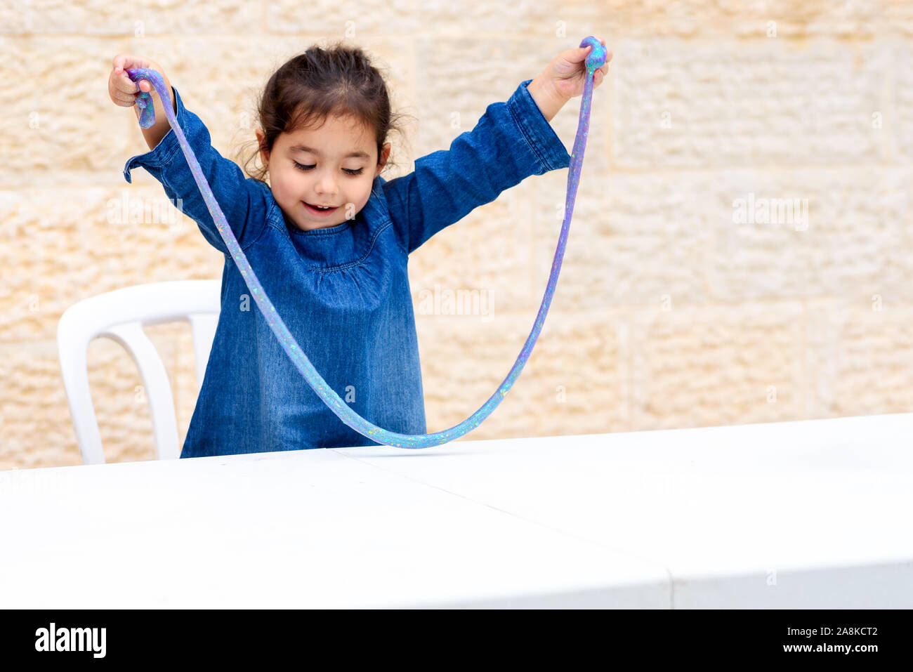 Smiling,laughing toddler girl playing with blue slime Stock Photo - Alamy