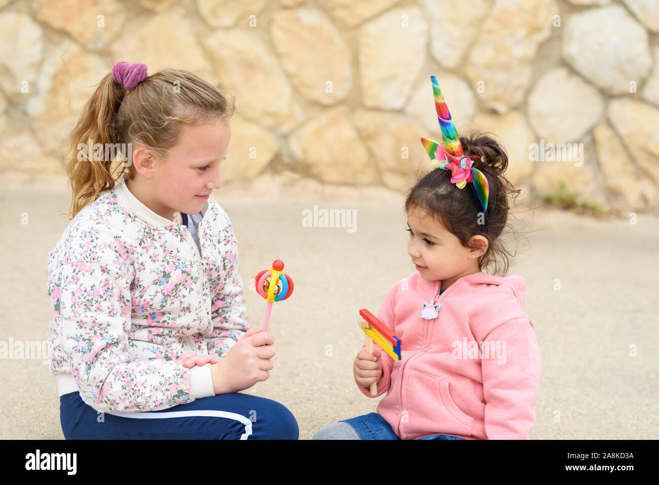Funny little girl holding wooden grogger and happy toddler girl dressed ...