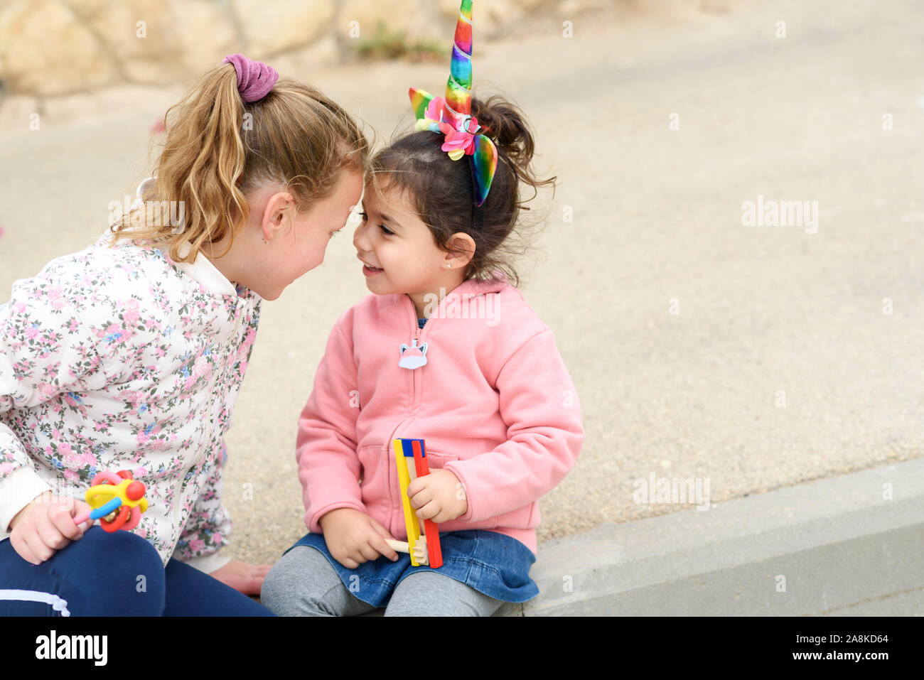Funny little girl holding wooden grogger and happy toddler girl dressed ...