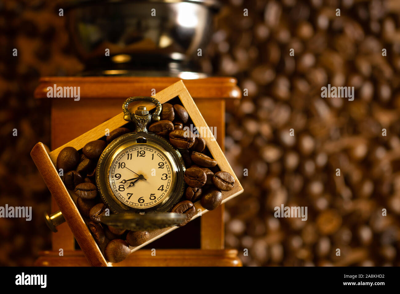 Coffee bean and pocket watch the tray of manual grinder on table. Top ...