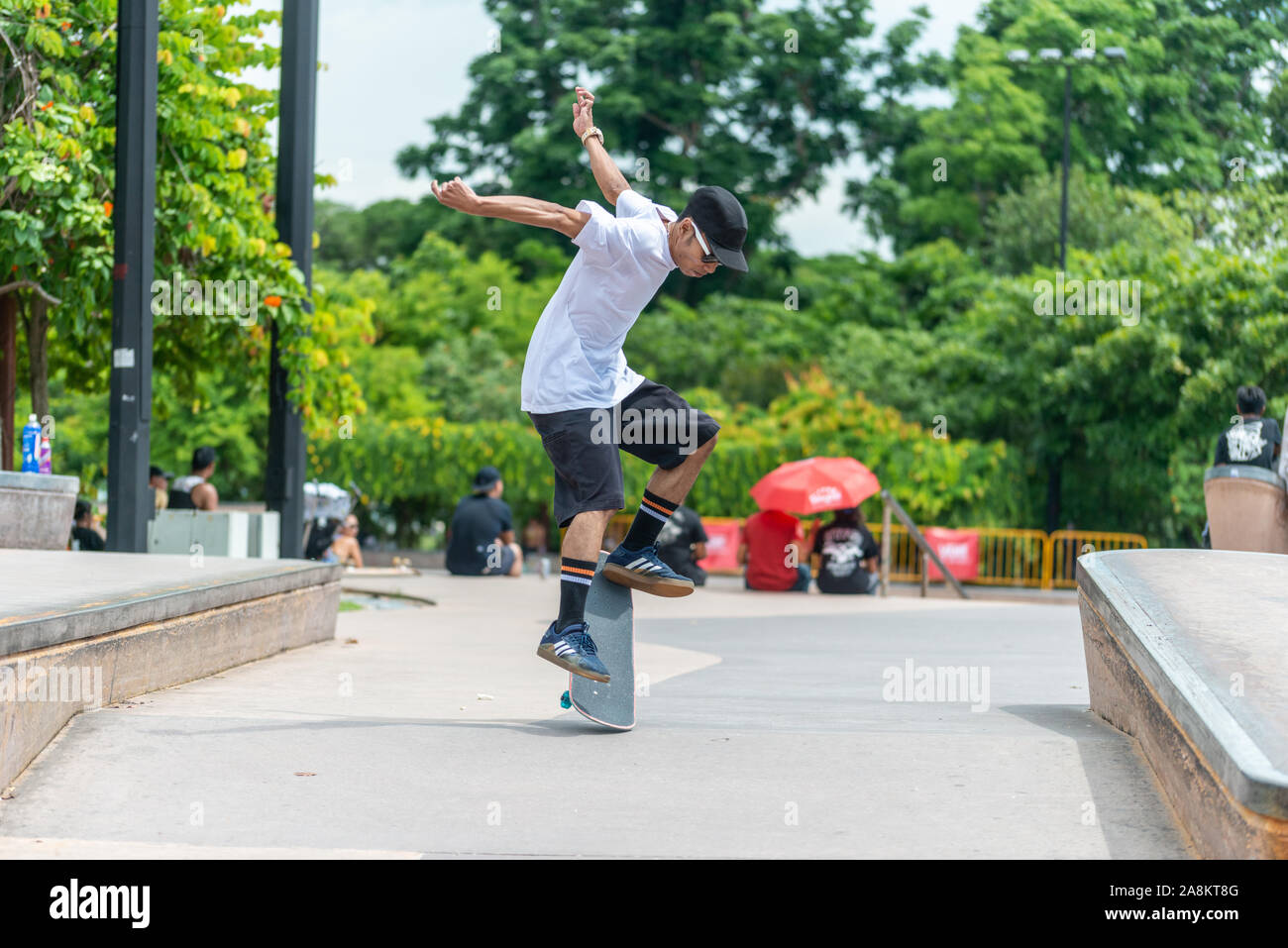 Young asian male boy skater displaying board skating skills outdoor in ...