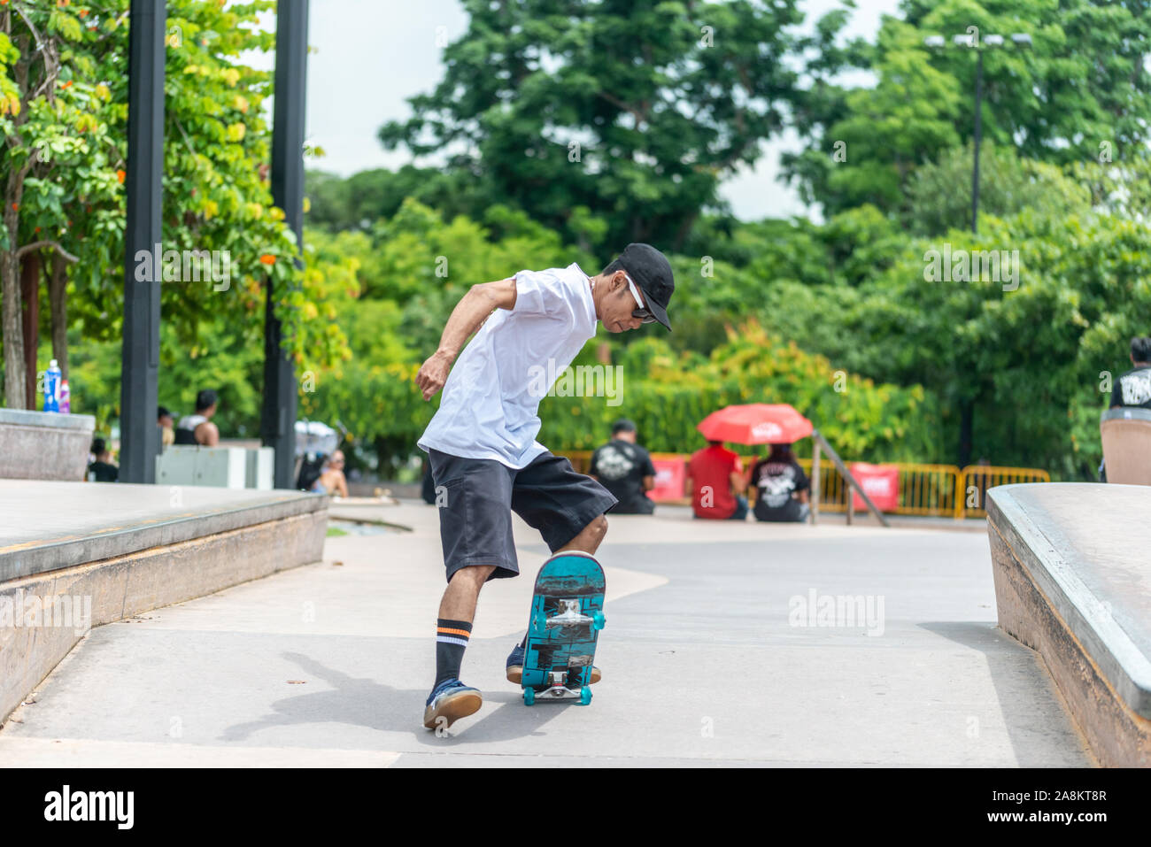 Young asian male boy skater displaying board skating skills outdoor in ...