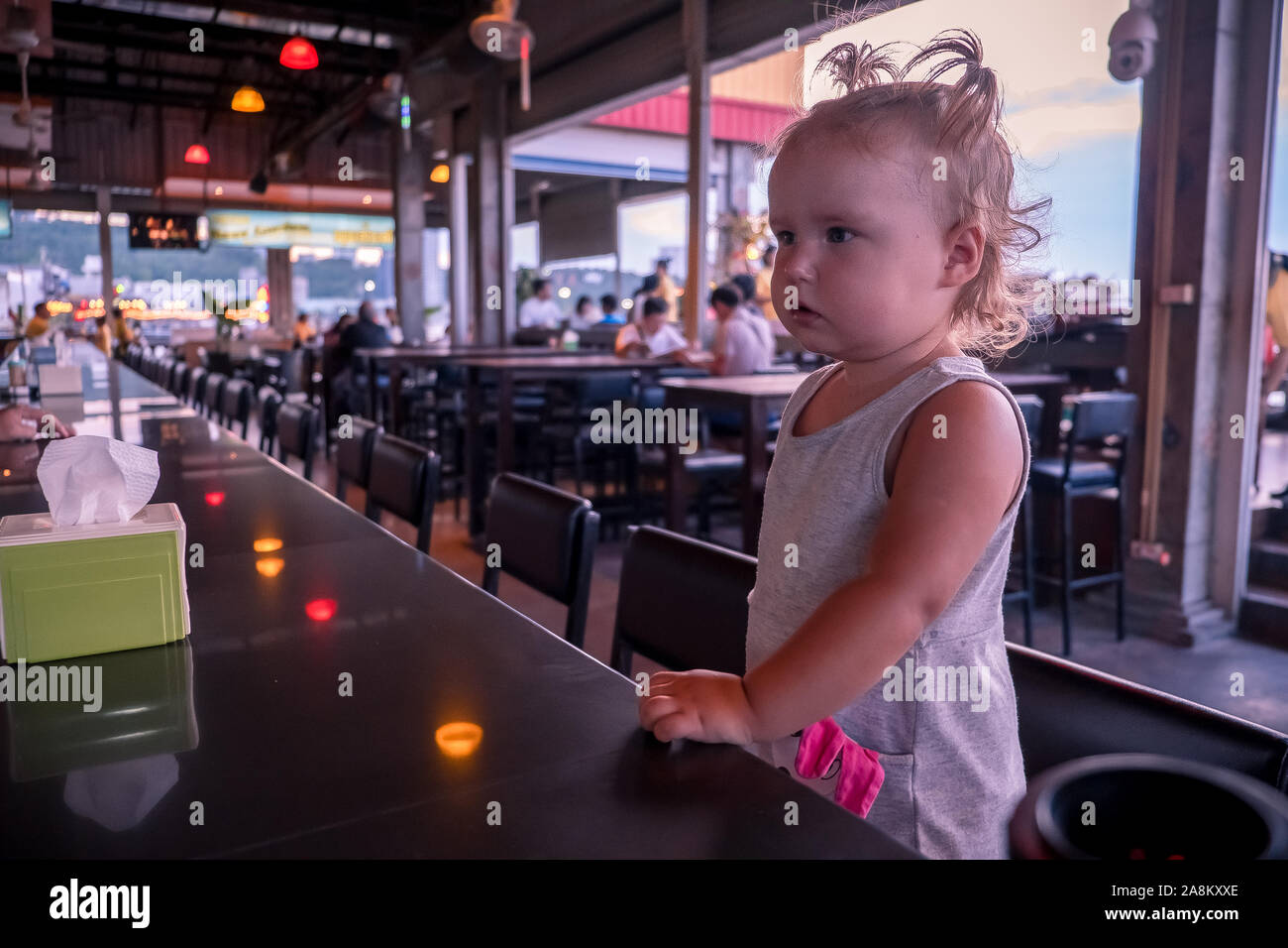 happy little girl sits in a cafe in the evening Stock Photo - Alamy