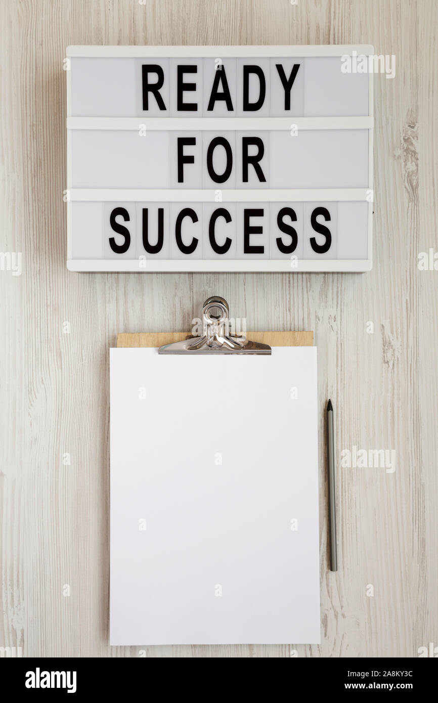 'Ready for success' words on a lightbox, clipboard with blank sheet of ...
