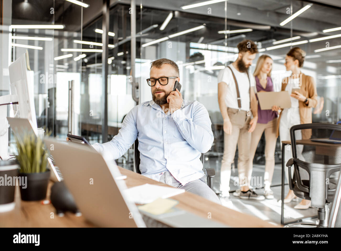 Senior confident manager working in the modern office with employees ...