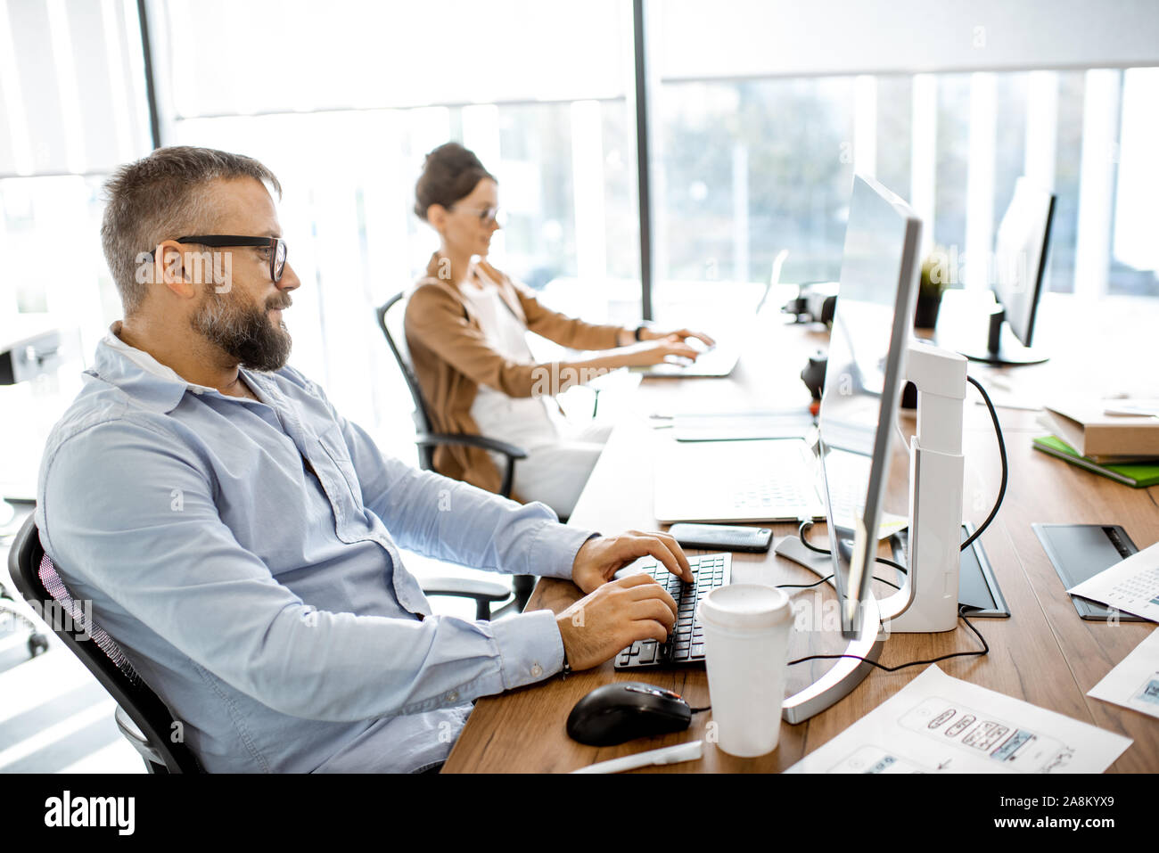 Senior programmer working on the computer in the modern office with ...