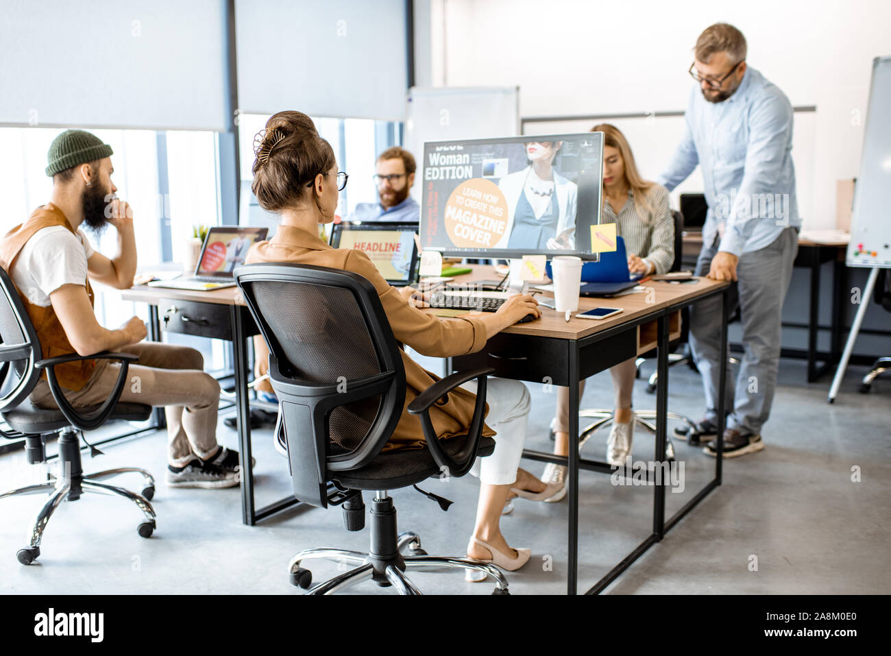 Group of diverse and creative colleagues working on computers in the ...