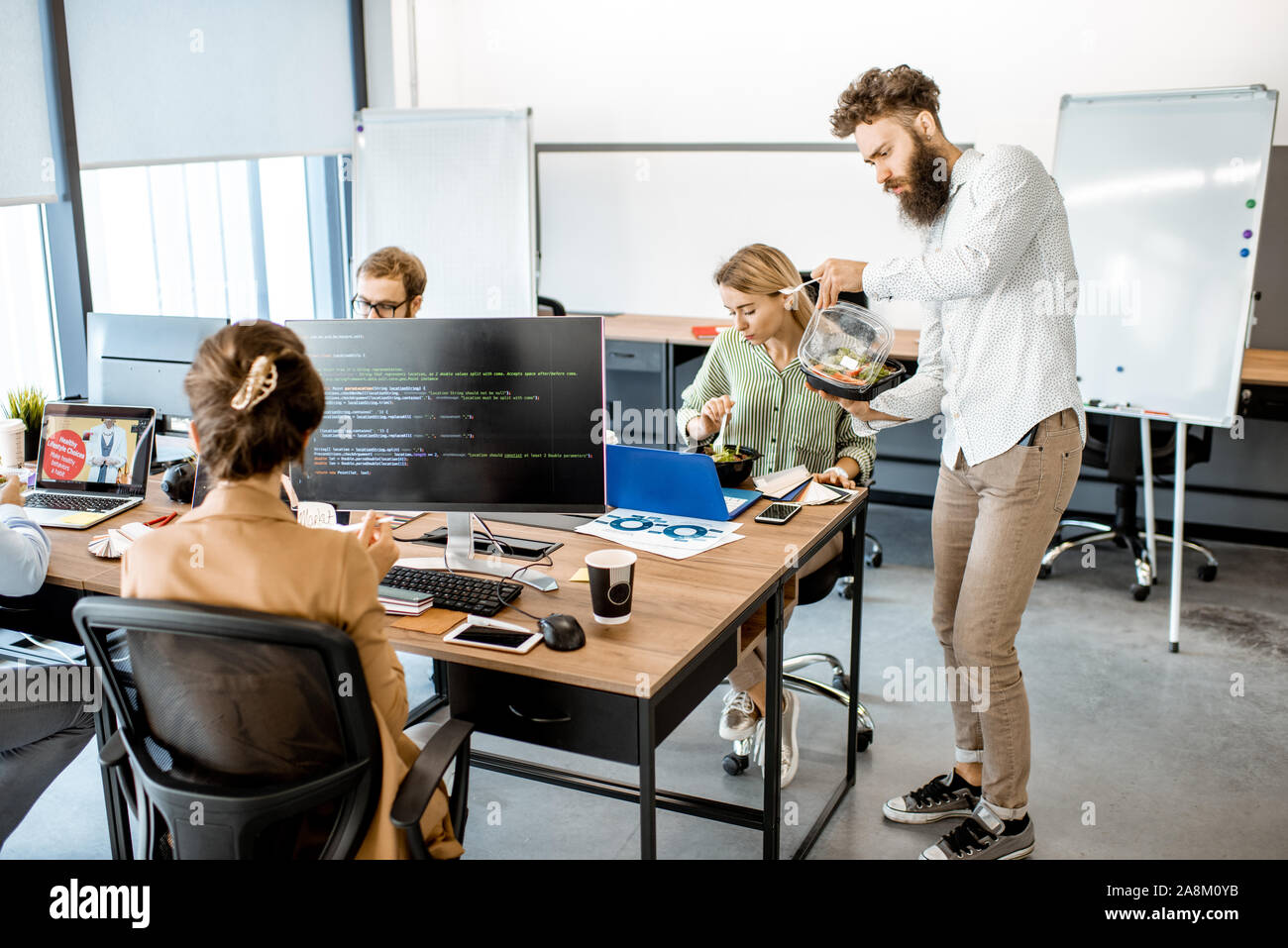 Office workers eating salad while sitting on the working place during a ...