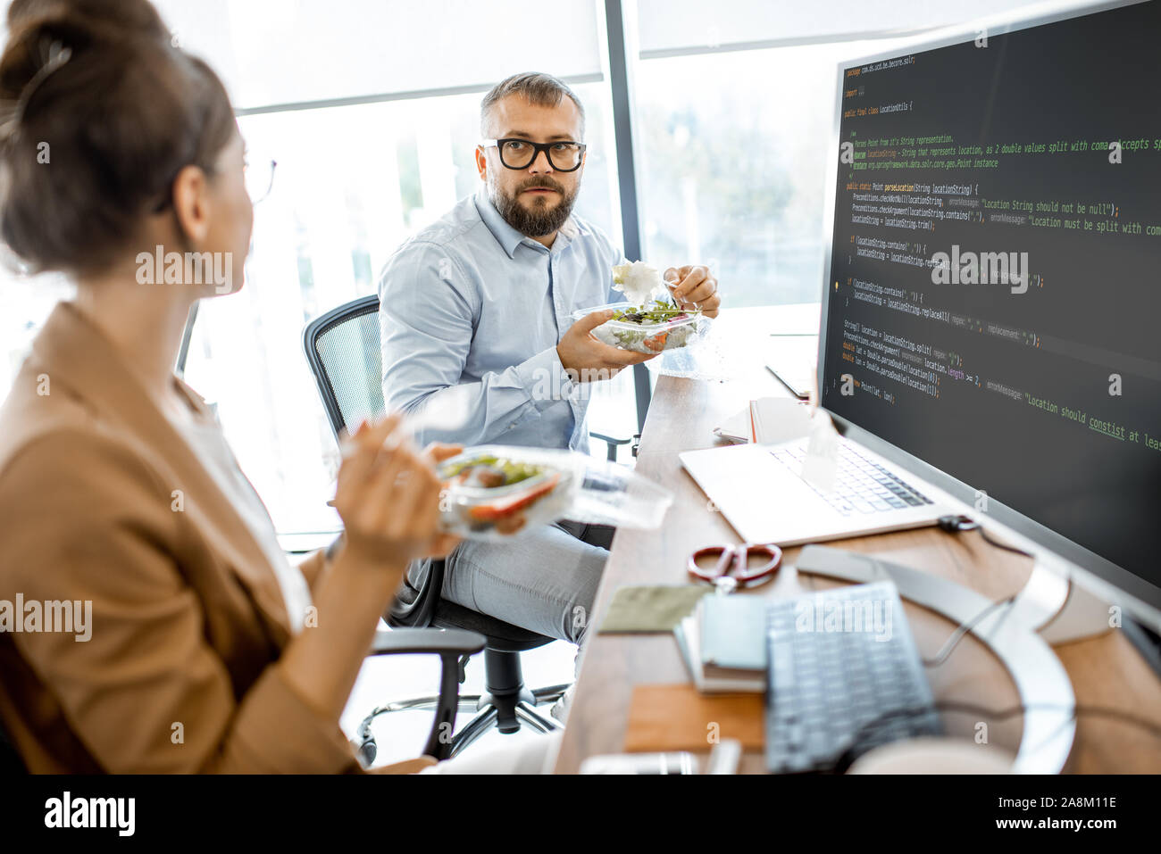 Man and woman eating salad during a lunch time on the working place ...