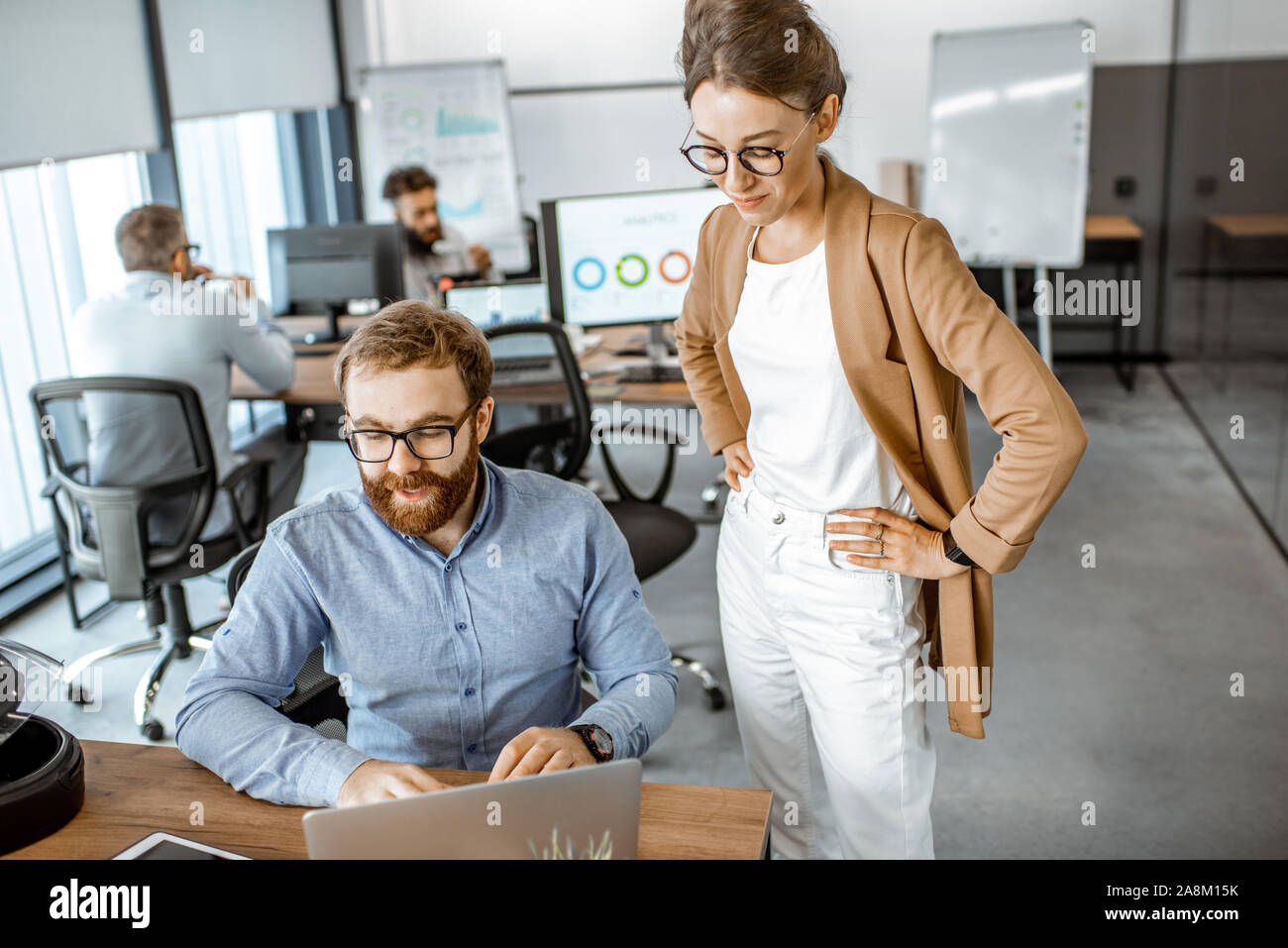 Two young colleagues talking at the working place, solving some working ...