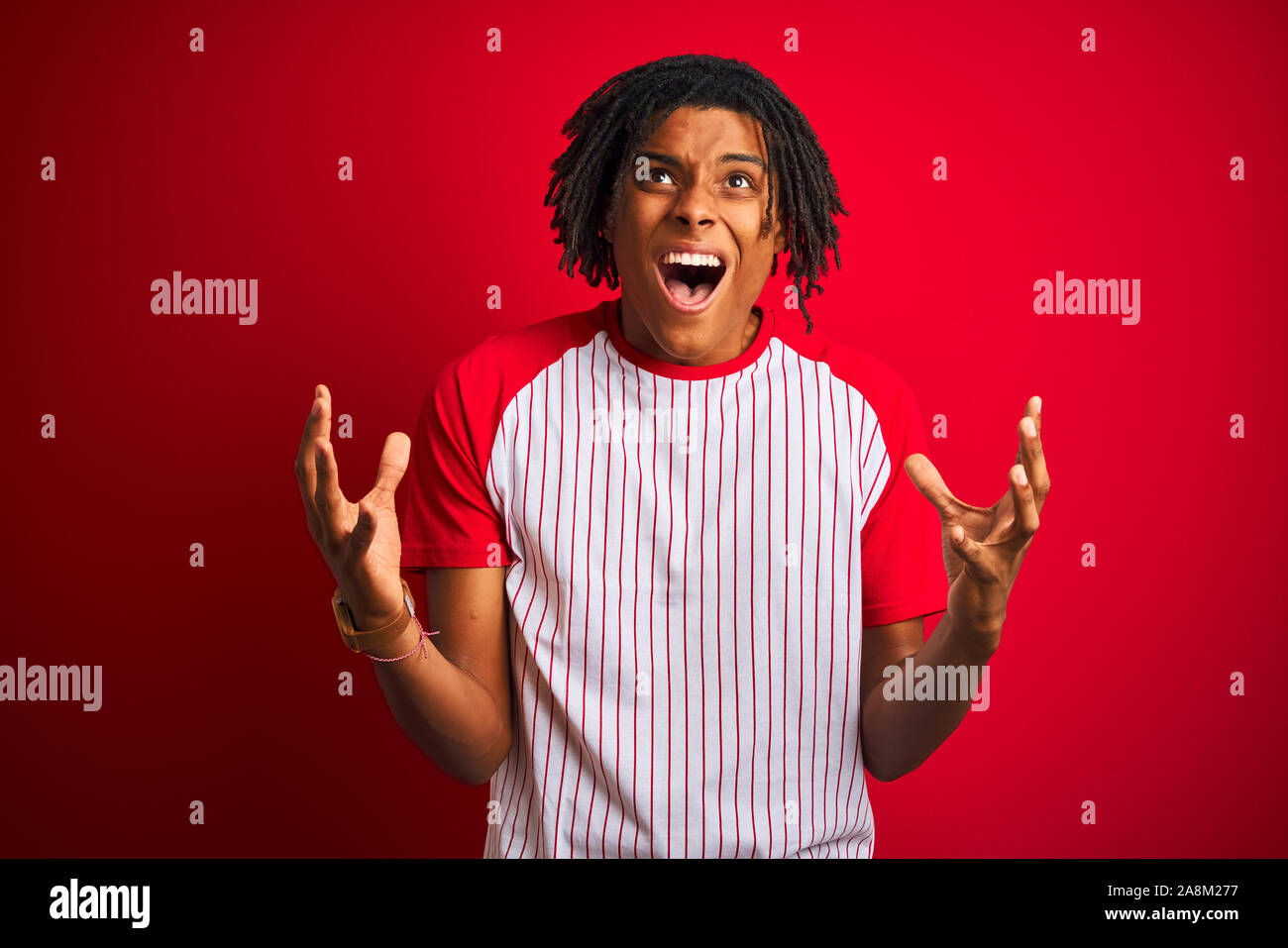 Afro man with dreadlocks wearing striped t-shirt standing over isolated ...