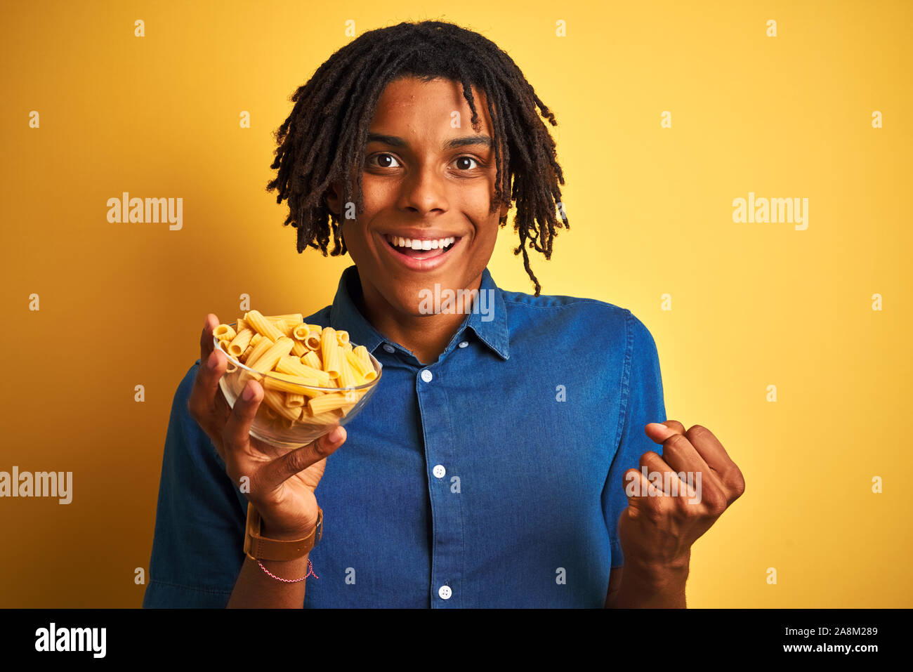Afro american man with dreadlocks holding pasta macaroni over isolated ...