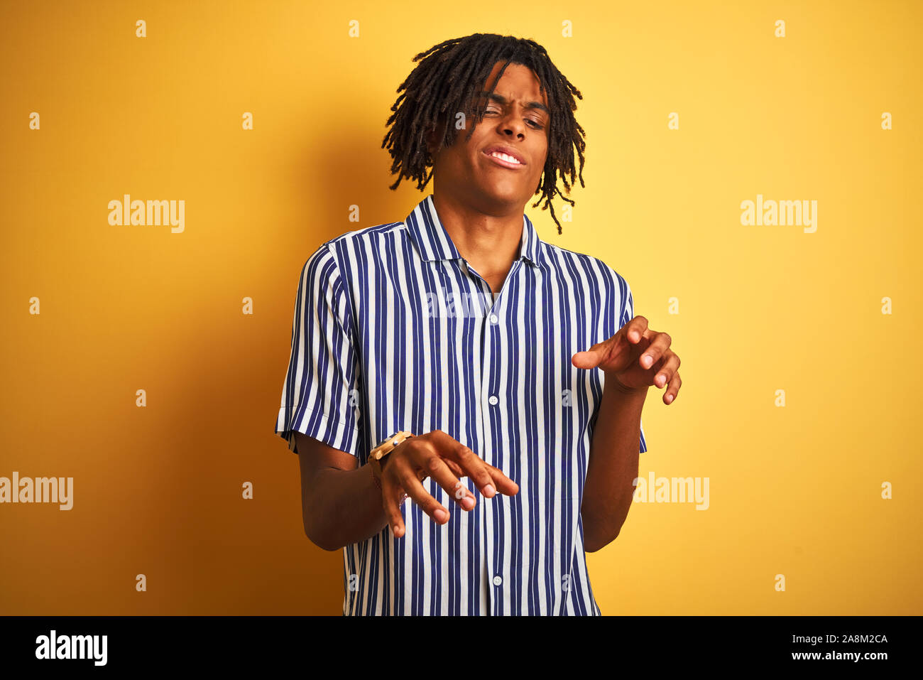 Afro man with dreadlocks wearing casual striped t-shirt over isolated ...