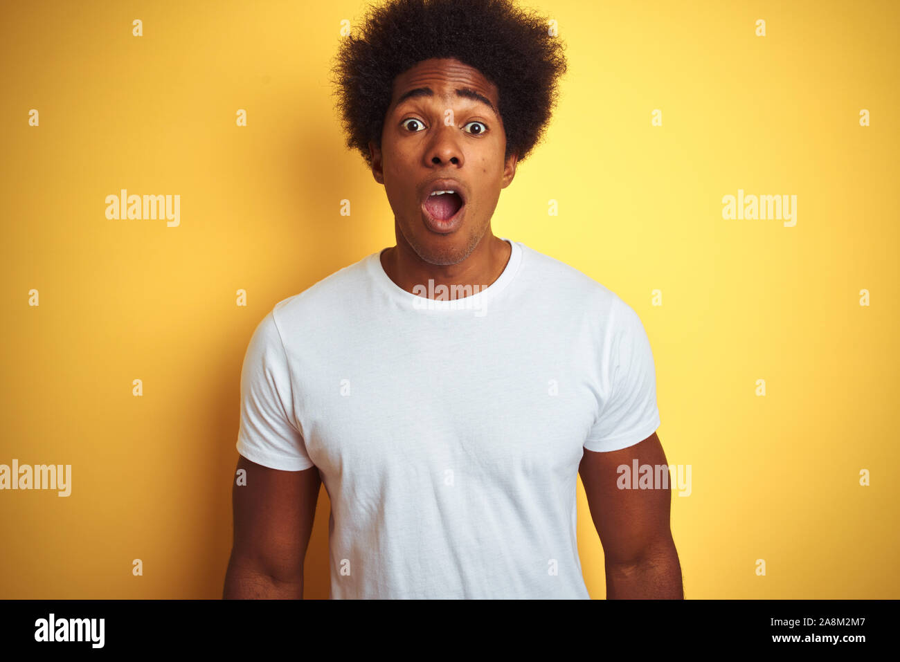 American man with afro hair wearing white t-shirt standing over ...