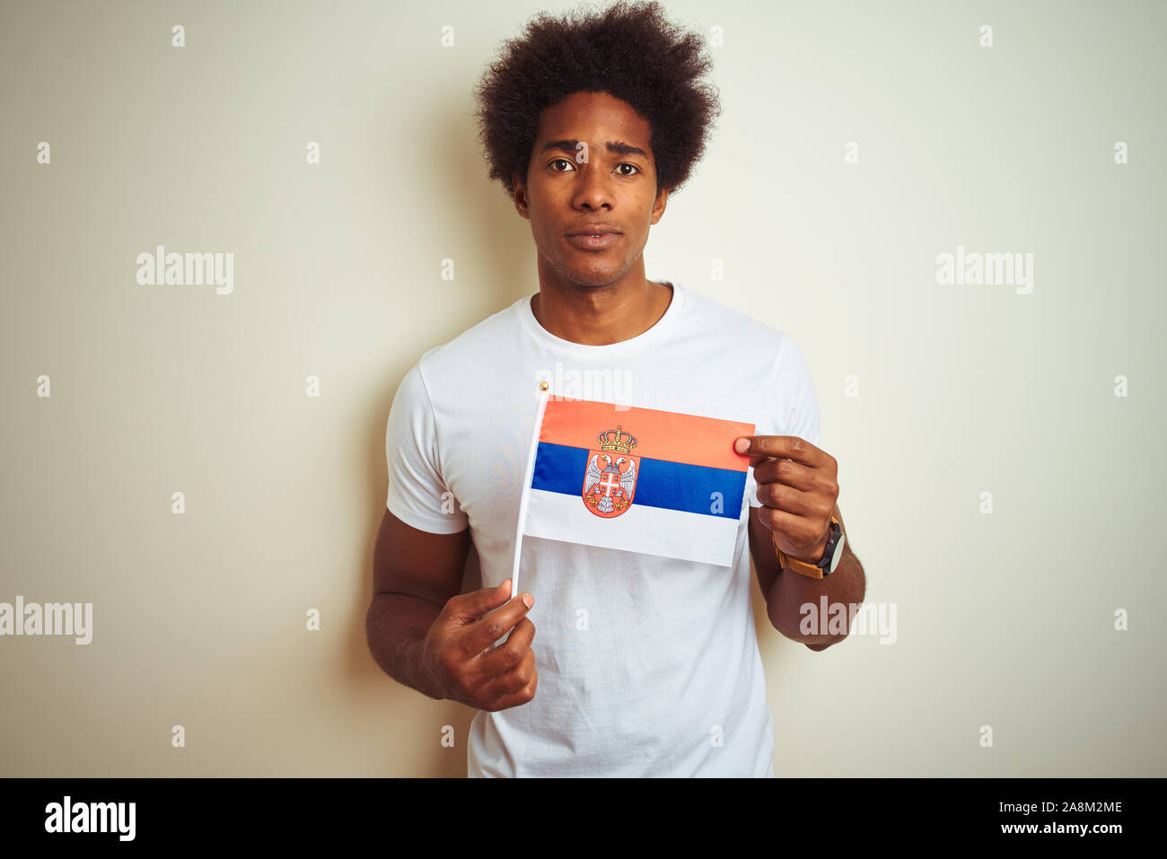 Young afro american man holding Serbia Serbian flag standing over ...