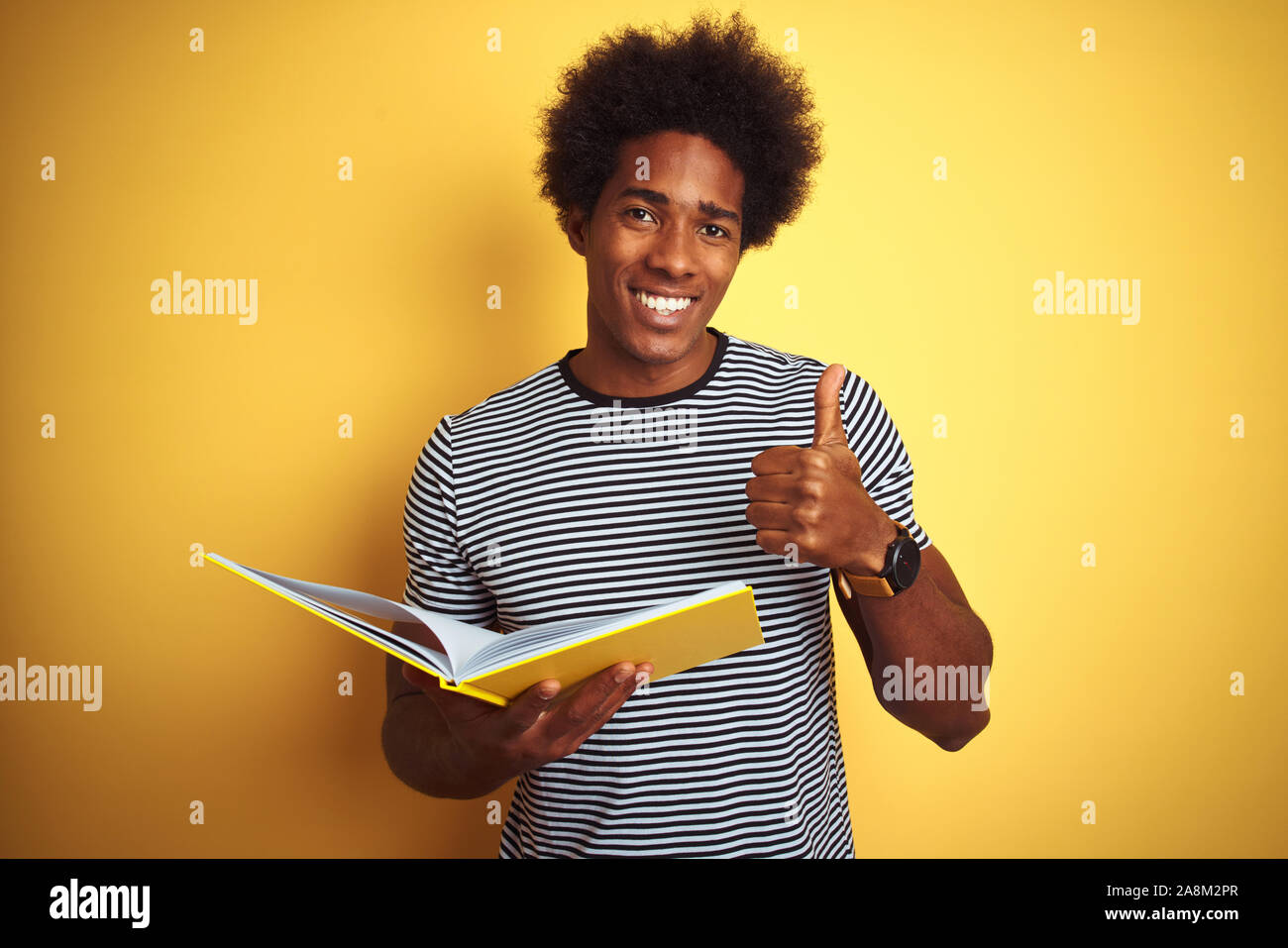 Afro american student man reading book standing over isolated yellow ...