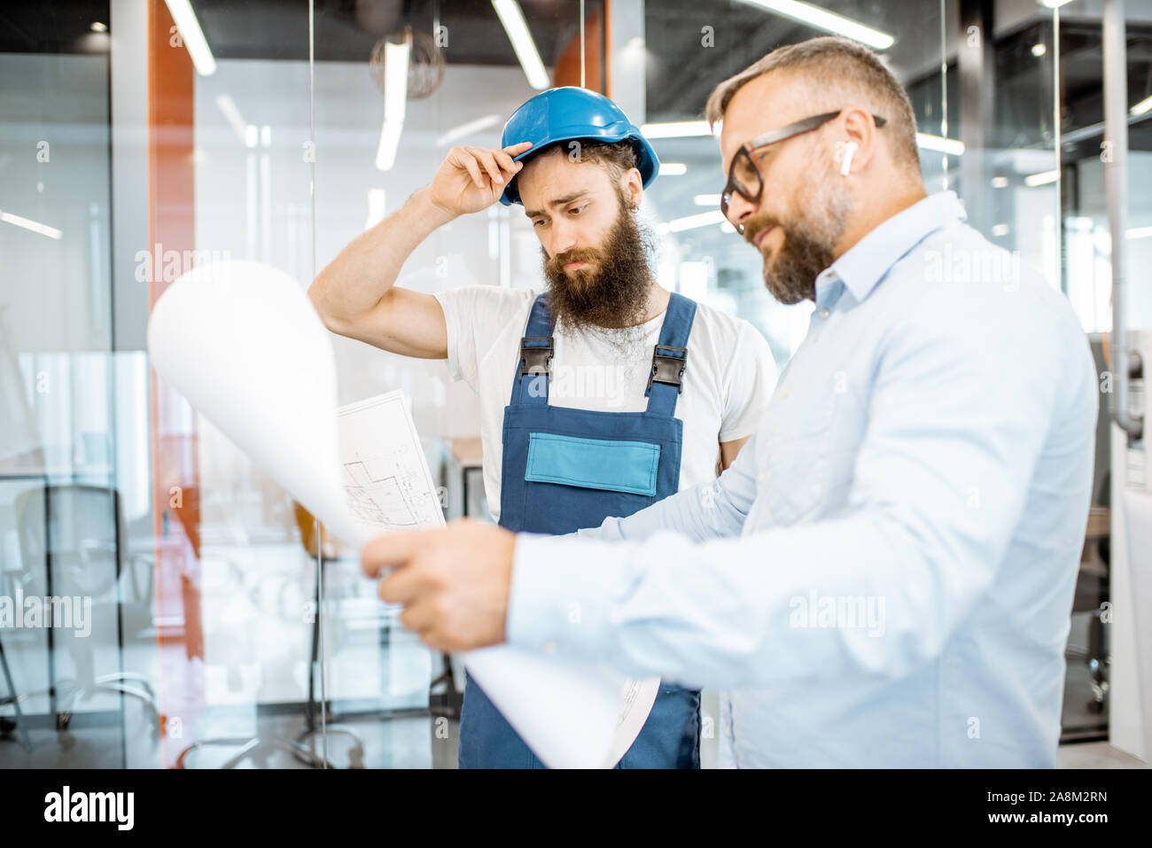 Senior foreman and workman in overalls working on project with ...
