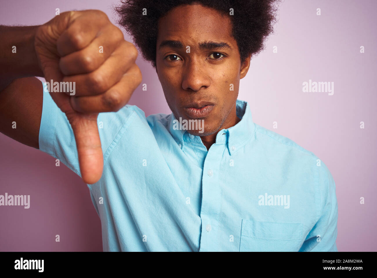 Young american man with afro hair wearing blue shirt standing over ...