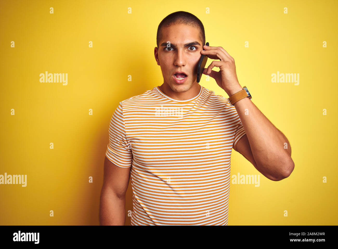Young handsome man talking using smartphone over yellow isolated ...