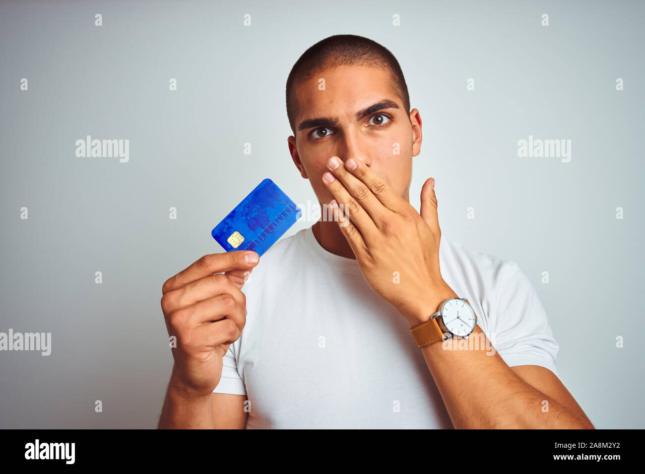 Young handsome man holding credit card over white isolated background ...