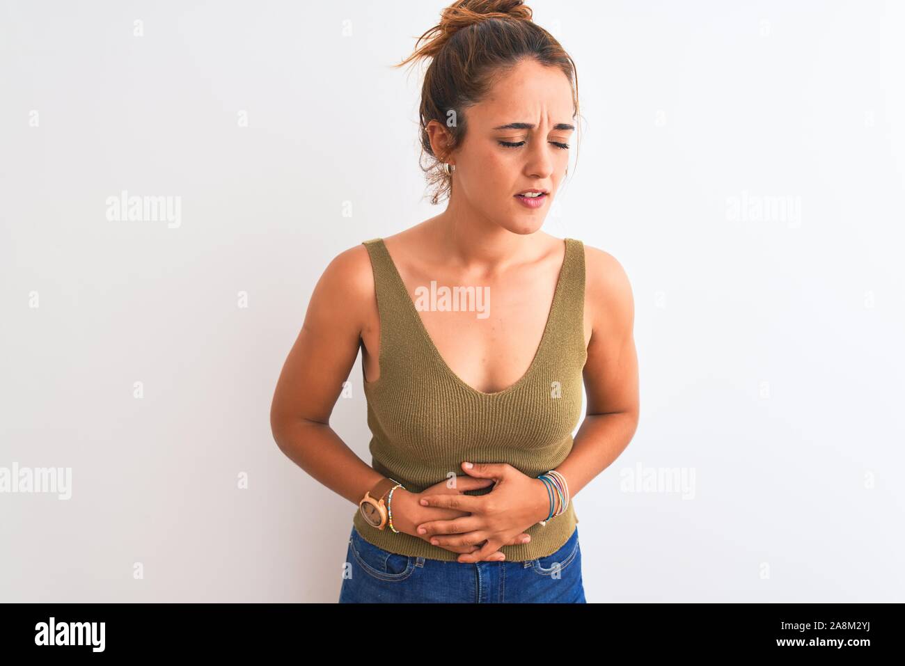 Young redhead woman wearing a bun over isolated background with hand on ...