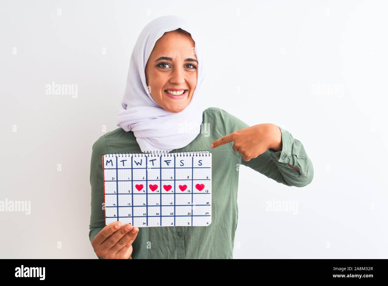 Young Arab woman wearing hijab showing menstruation calendar over ...