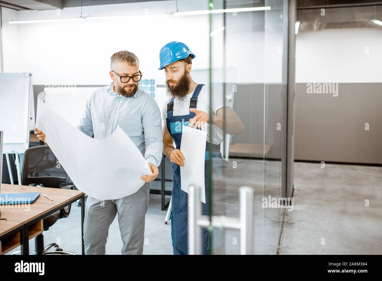 Senior foreman and workman in overalls working on project with ...