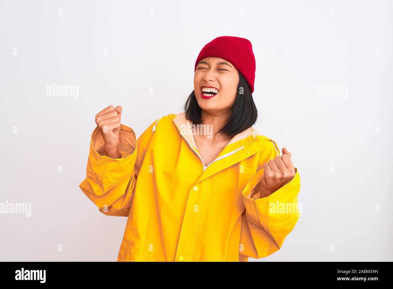 Young beautiful chinese woman wearing raincoat and wool cap over ...