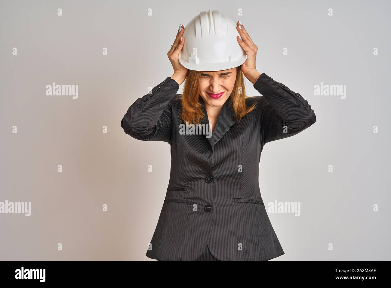 Redhead caucasian business woman wearing safety helmet over isolated ...