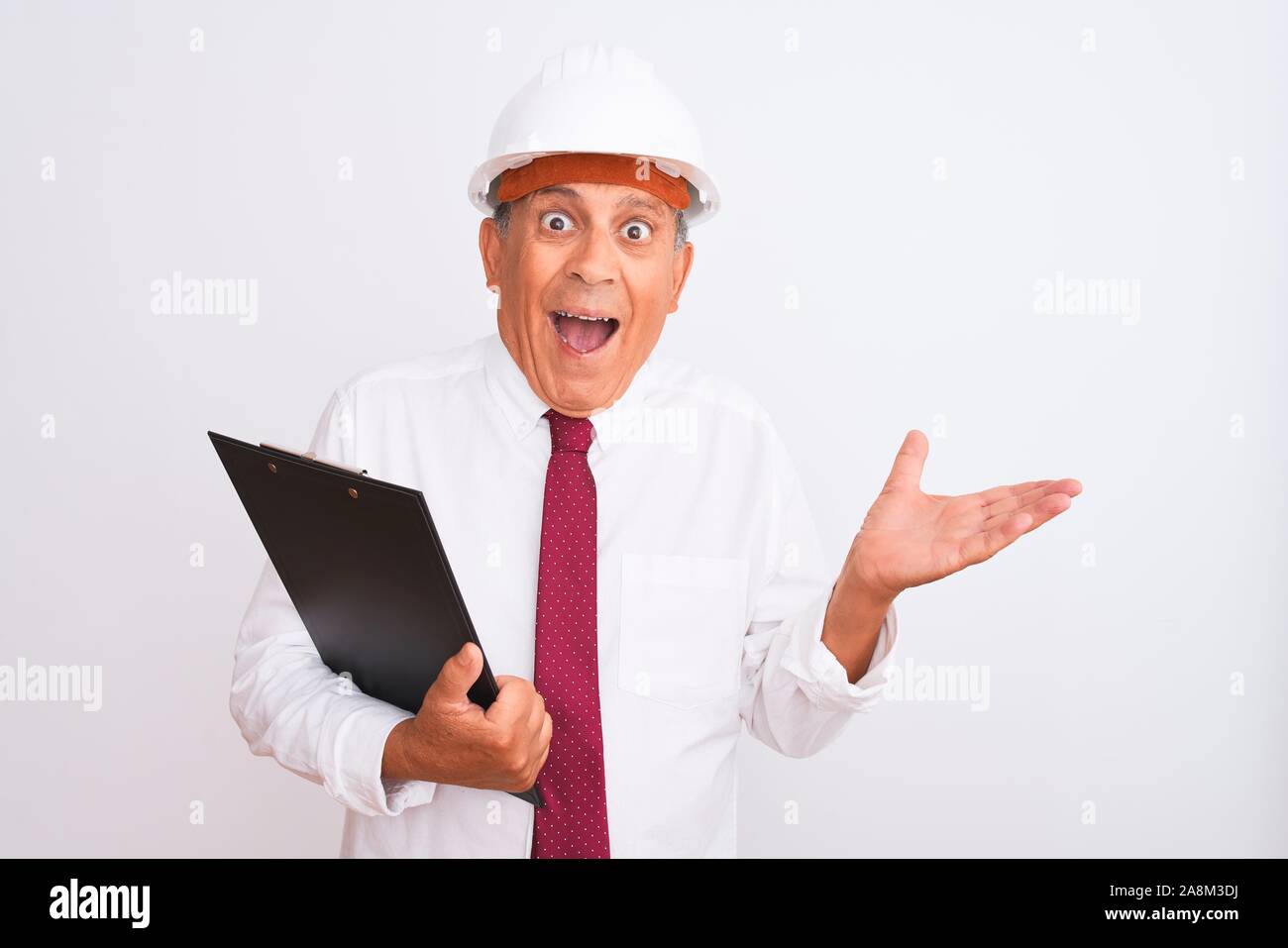 Senior architect man wearing security helmet holding clipboard over ...