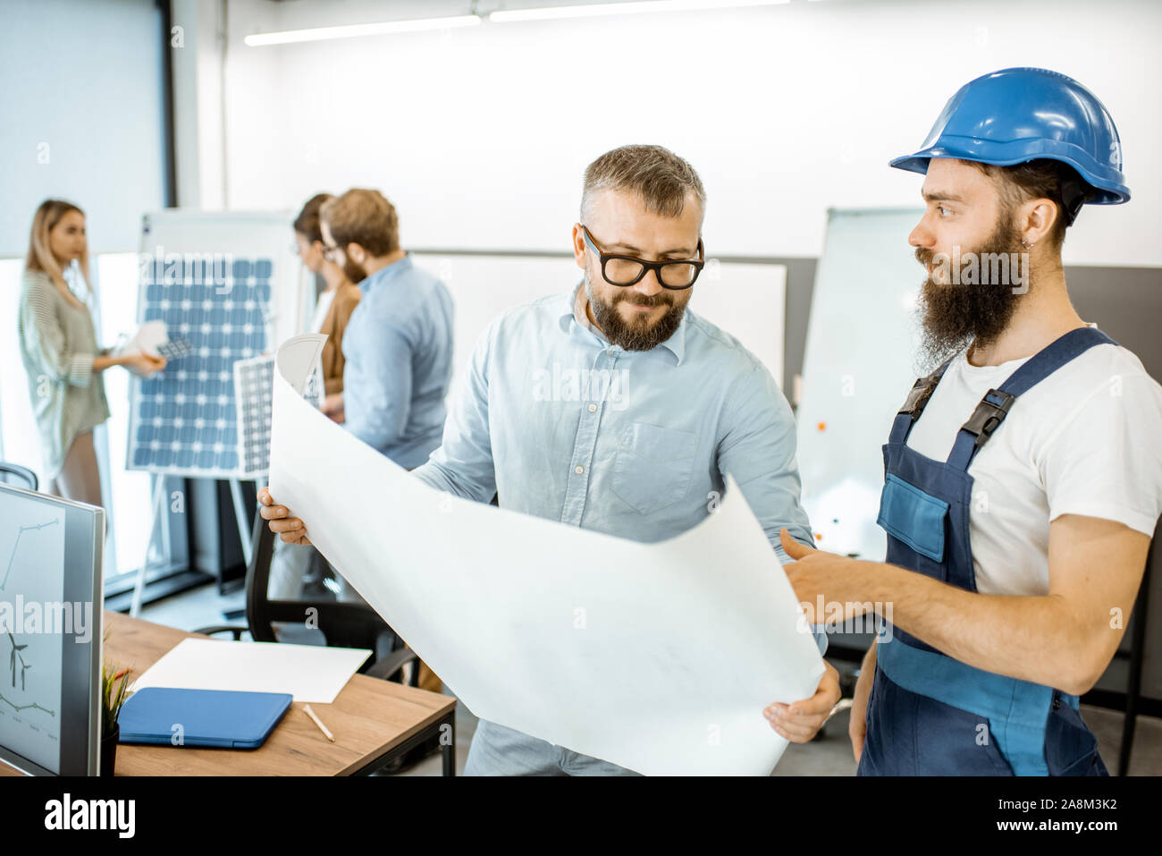 Senior foreman and workman in overalls working on project with ...