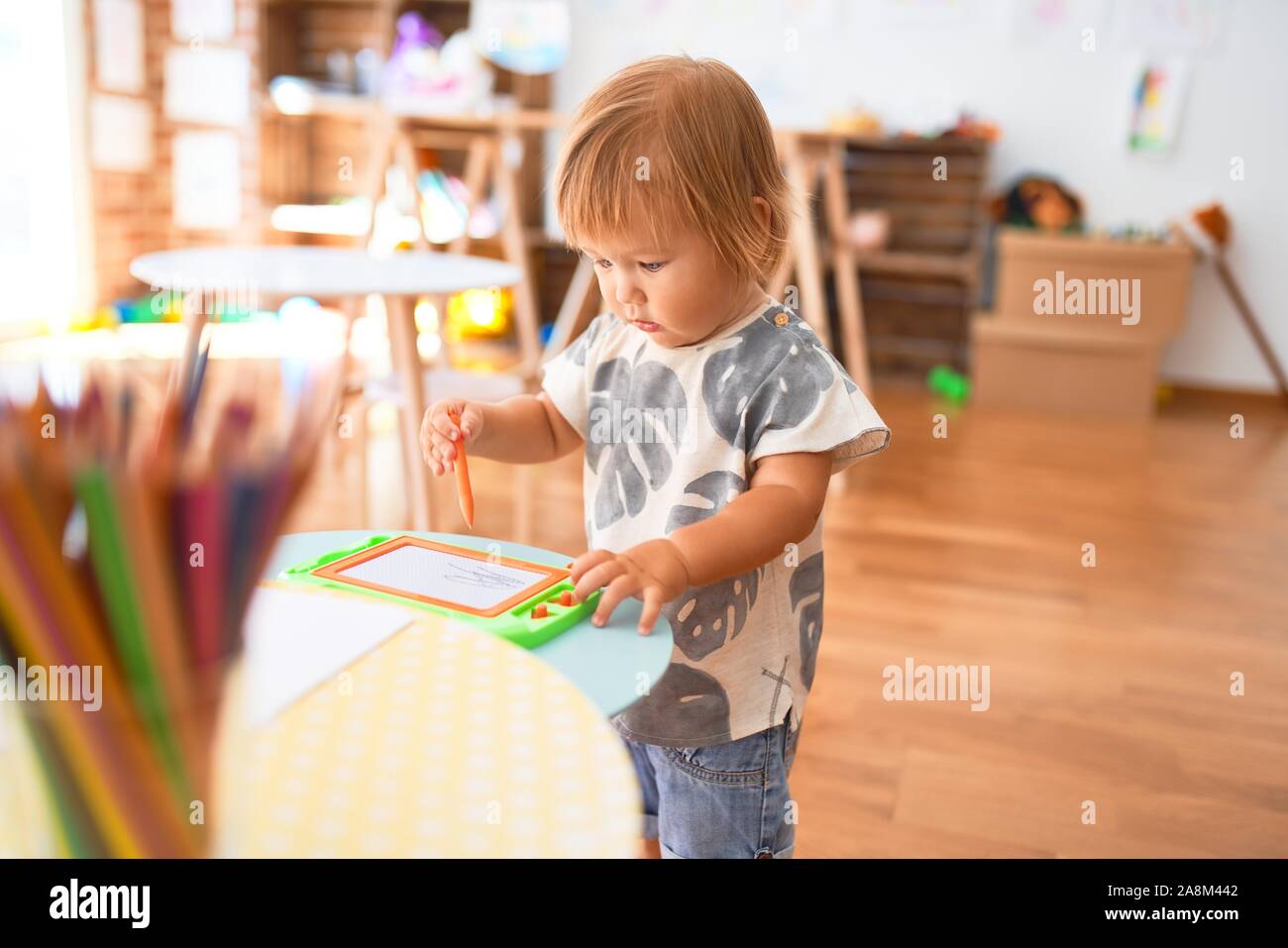 Adorable toddler drawing using digital board around lots of toys at ...
