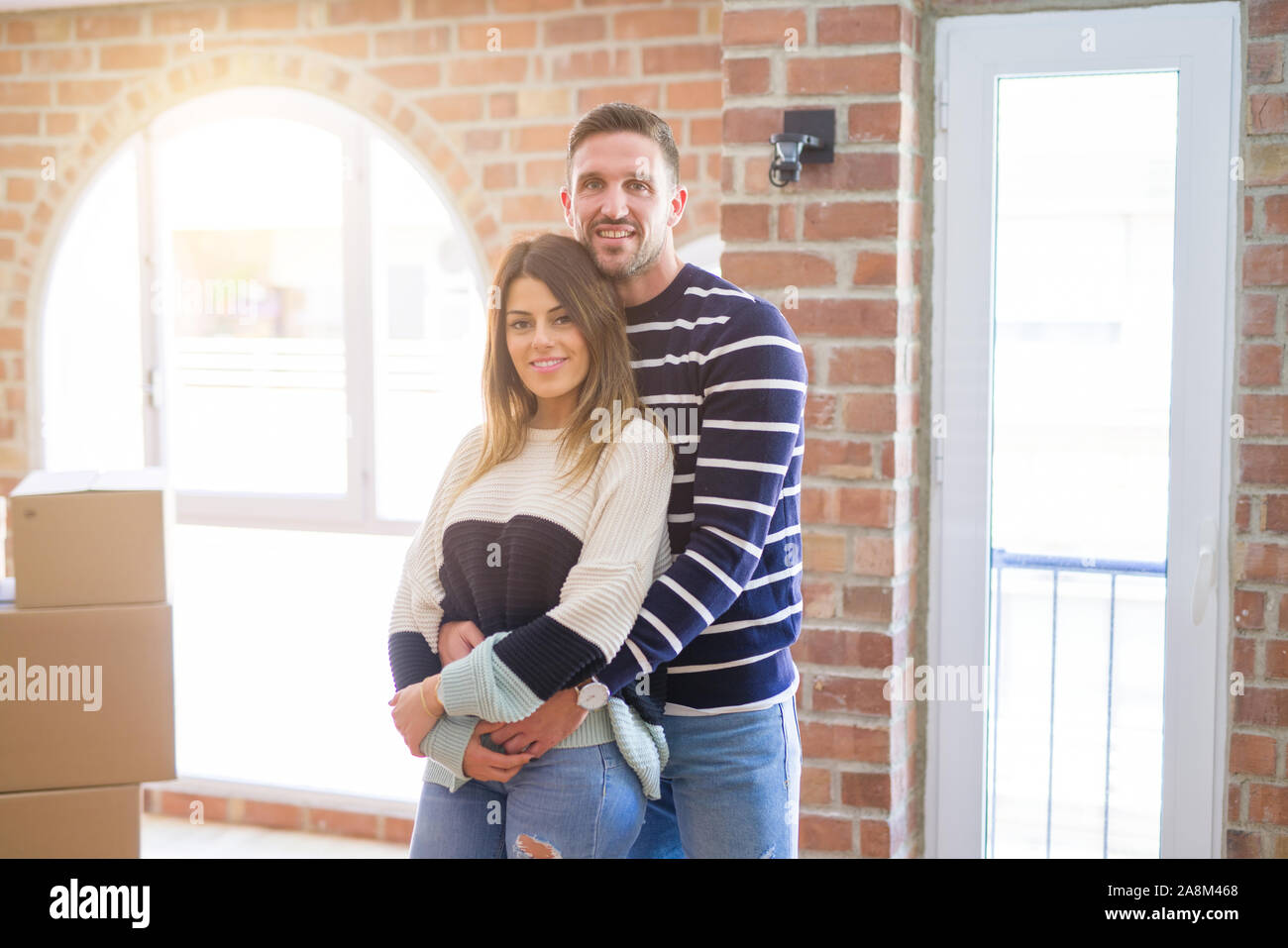 Young beautiful couple hugging at new home around cardboard boxes Stock ...