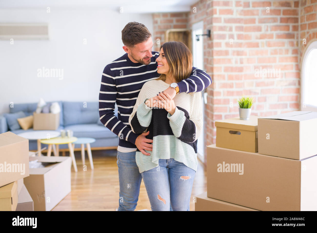 Young beautiful couple hugging at new home around cardboard boxes Stock ...