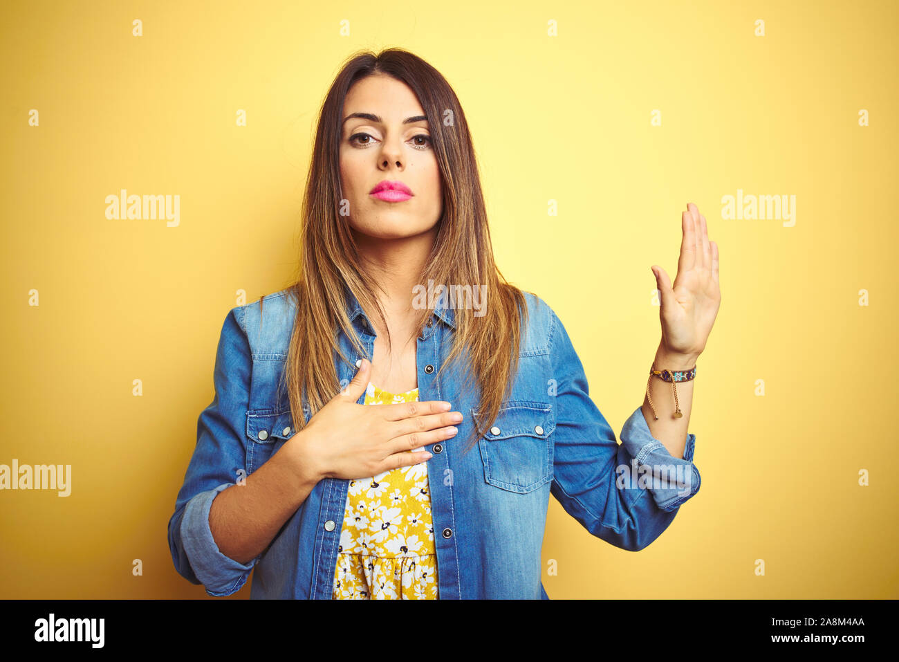 Young beautiful woman standing over yellow isolated background Swearing ...