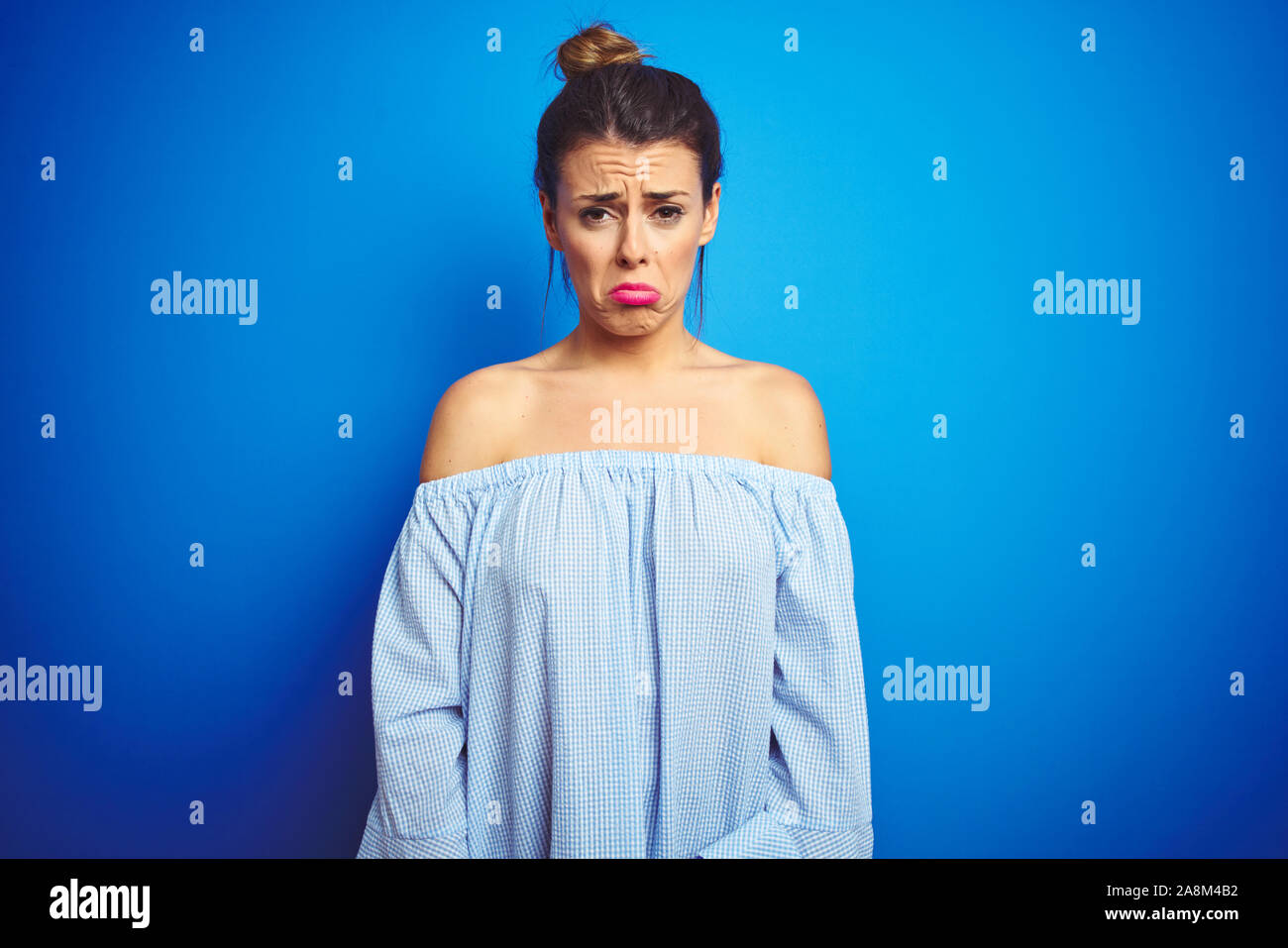 Young beautiful woman wearing bun hairstyle over blue isolated ...
