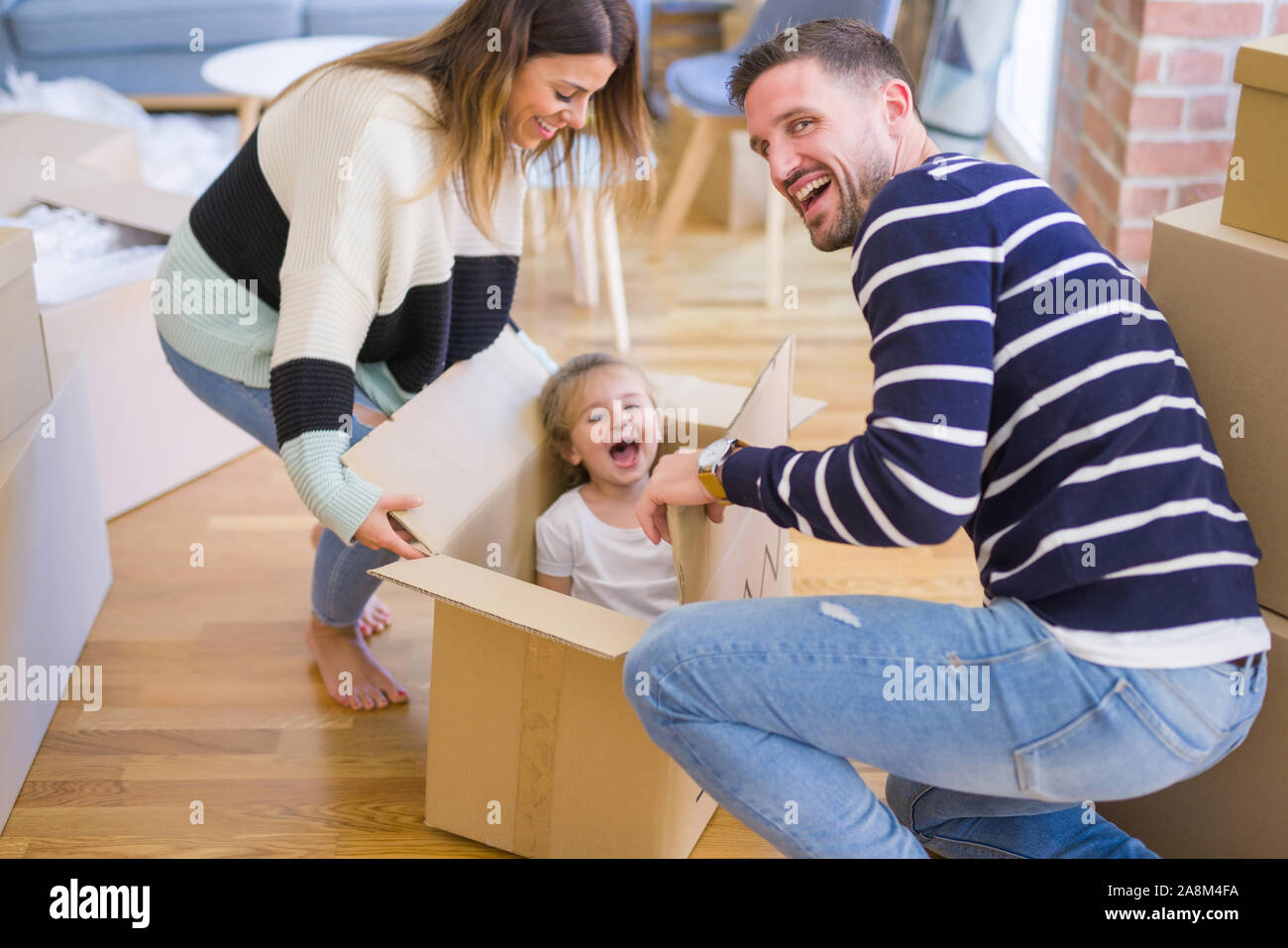 Beautiful famiily, kid playing with his parents riding cardboard fanny ...