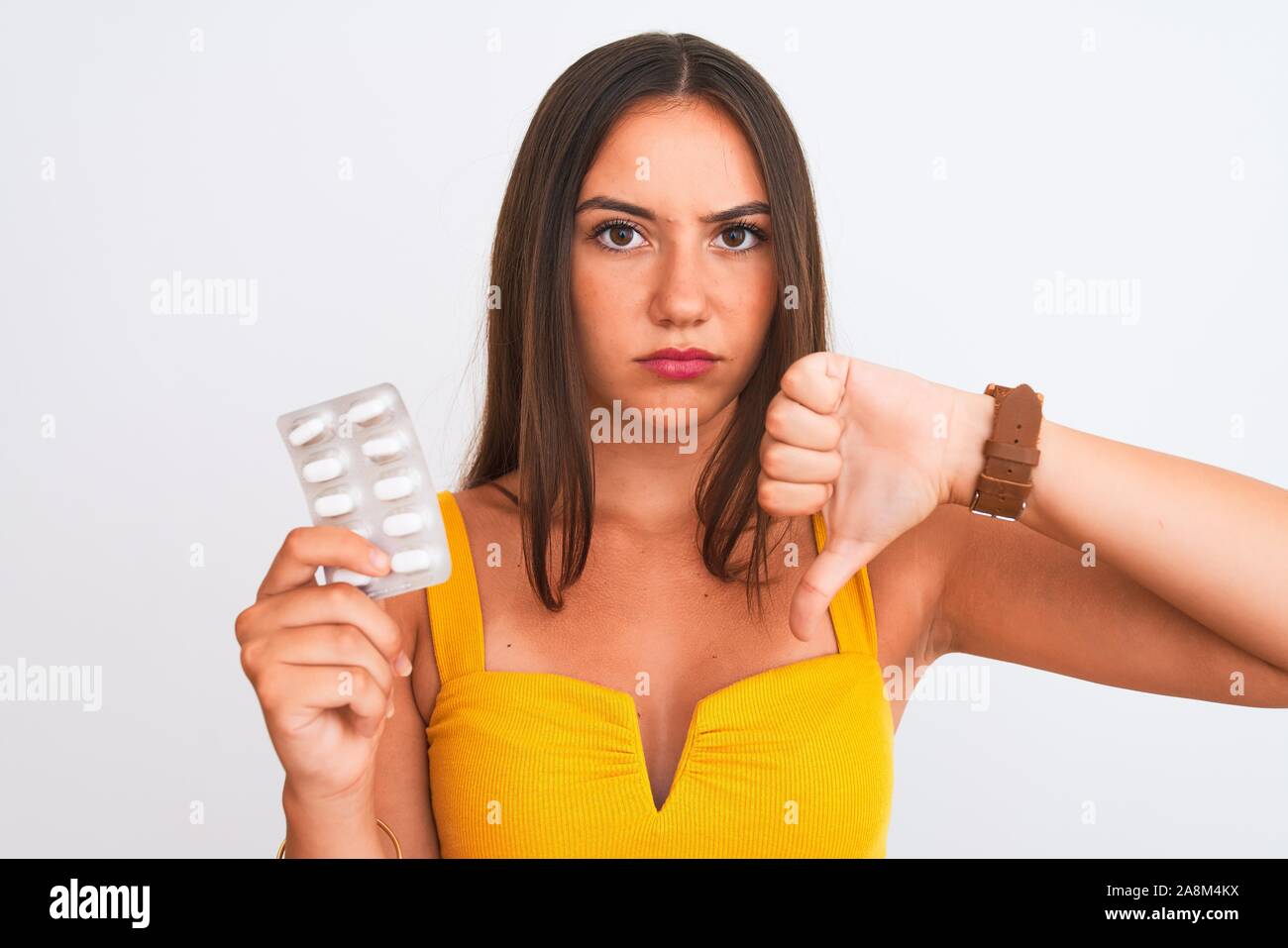 Young beautiful girl holding medicine pills standing over isolated ...