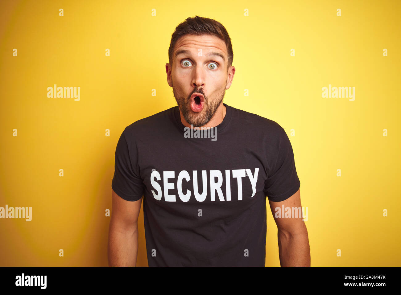 Young safeguard man wearing security uniform over yellow isolated ...