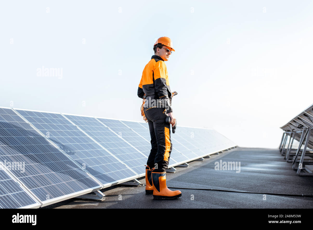 Well-equipped worker in protective orange clothing examining solar ...