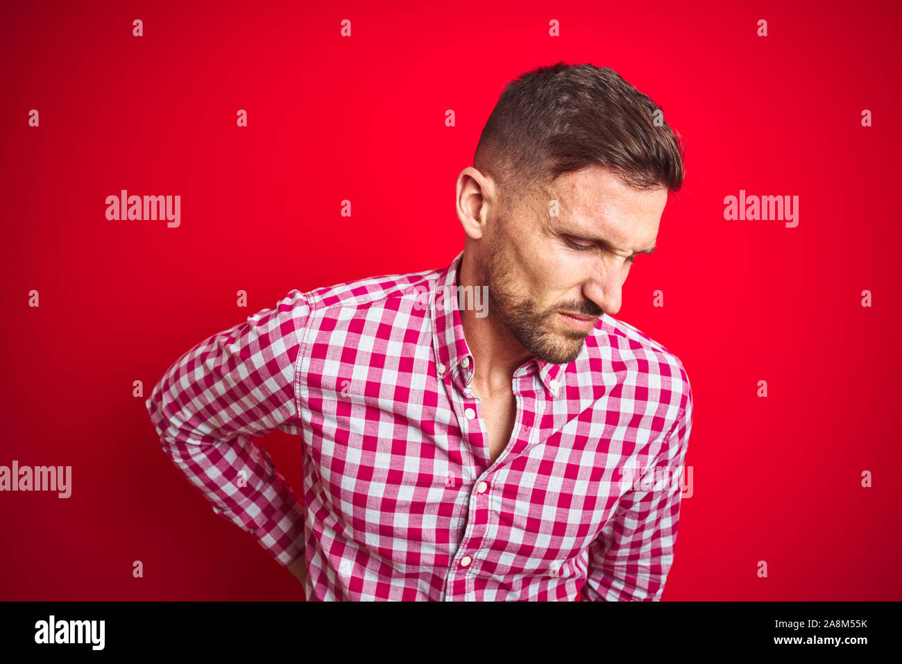 Young handsome man over red isolated background Suffering of backache ...